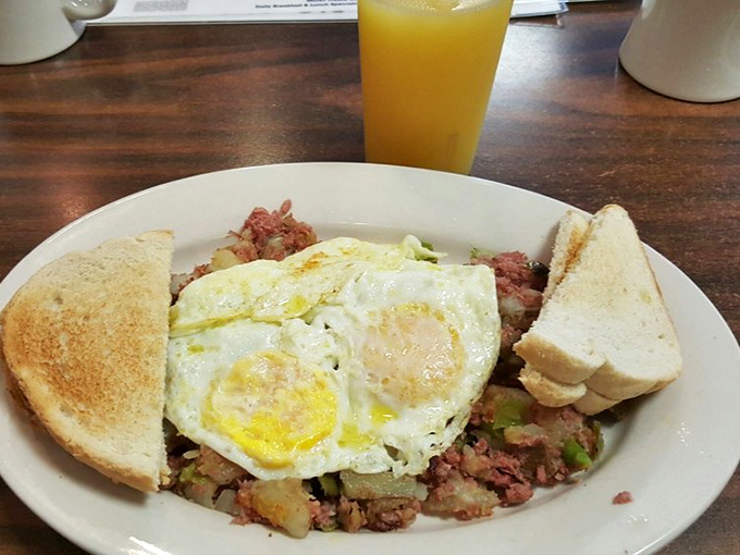 Breakfast nirvana: eggs sunny-side up creating golden rivers across a landscape of savory corned beef hash, with toast standing by for the crucial mop-up operation.