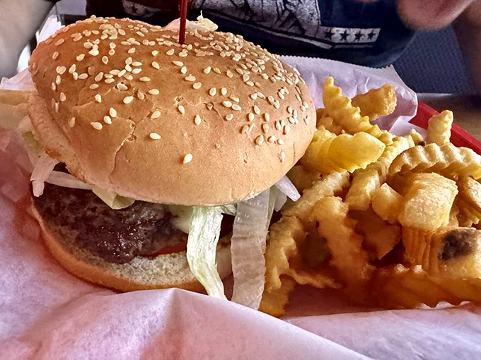 Burger architecture 101: A perfectly proportioned stack of beef, veggies, and sesame-studded bun alongside golden crinkle-cut fries. Textbook delicious.