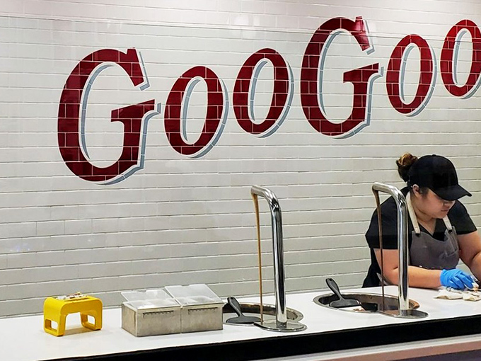 The ingredient display wall reveals the building blocks of greatness: peanuts, marshmallow nougat, caramel, and milk chocolate waiting to become something magical.