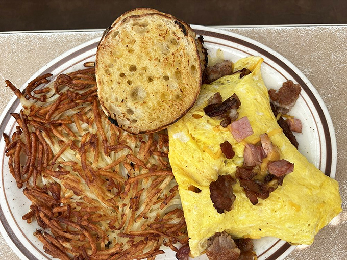 Hash browns that achieve the impossible—crispy exterior, tender interior—flanking an omelet that's practically bursting with savory fillings. Breakfast nirvana achieved.