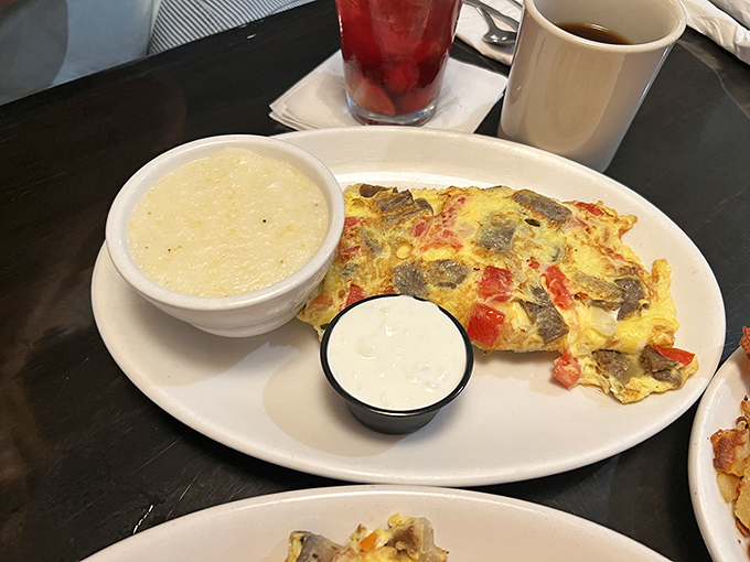 This isn't just an omelet; it's a masterclass in breakfast architecture. Fluffy eggs cradle savory fillings with grits standing by for backup.