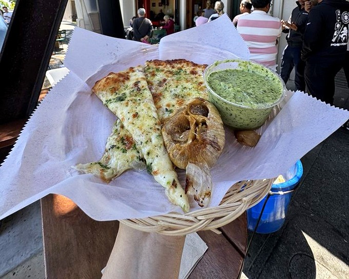 Two slices and a roasted garlic bulb—nature's butter. The green sauce adds a zingy counterpoint to the pizza's richness.