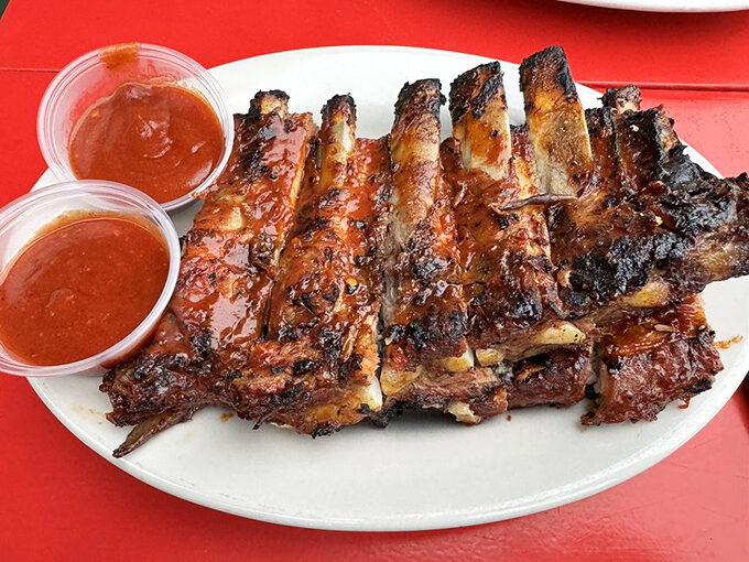 Ribs that wear their char marks like badges of honor, glistening with sauce and practically begging you to abandon all dining etiquette.