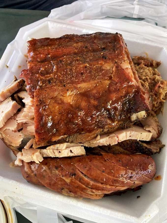 Ribs and pulled pork sharing a container like old friends at a reunion. The glistening bark says everything about the smoking process.