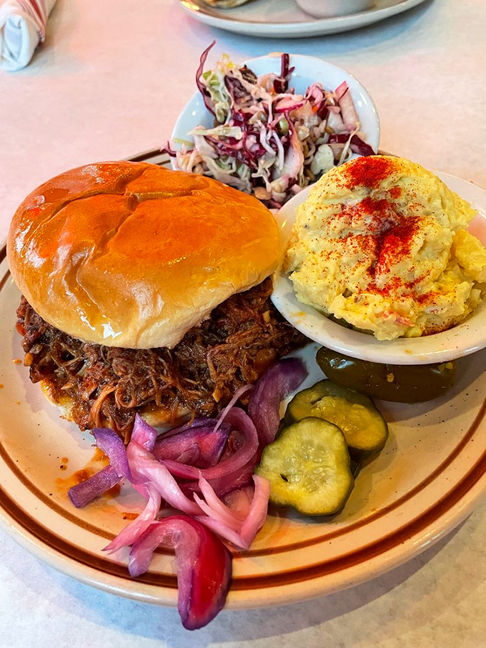 This isn't just a sandwich—it's an architectural marvel of pulled pork, pickles, and onions that requires both hands and possibly a bib.