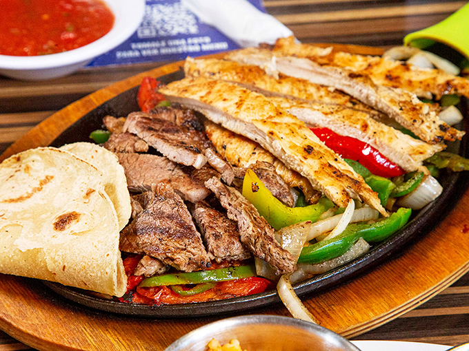 Sizzling fajitas that announce their arrival before you see them – a theatrical presentation of perfectly grilled meats and vibrant peppers on a wooden platter.