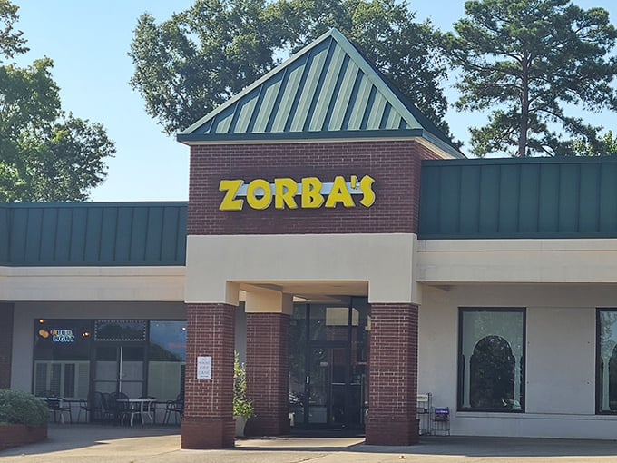Zorba's bold yellow sign against brick and green roof creates an unexpected pizza paradise where Greek and Italian traditions meet deliciously.