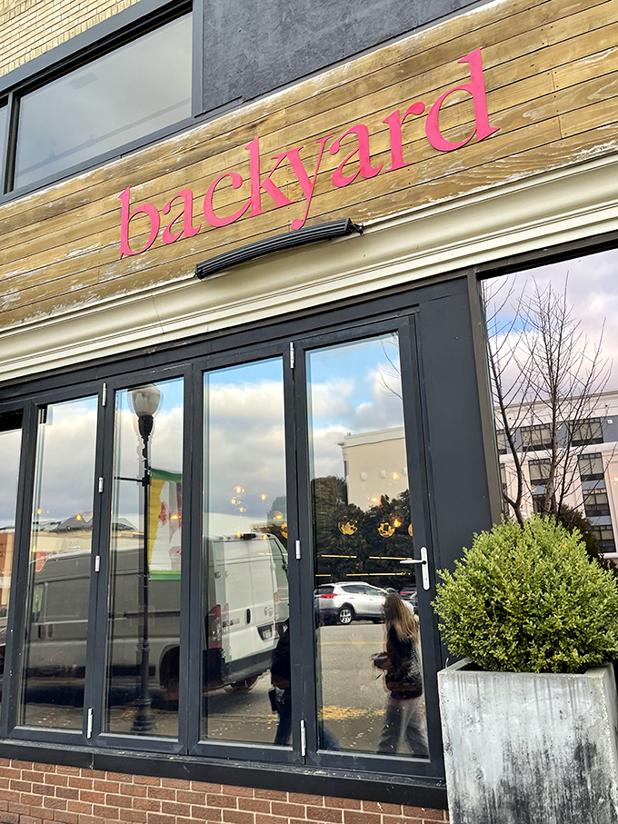 That pink "backyard" sign glows like a beacon for pizza lovers seeking wood-fired perfection in downtown Huntington.
