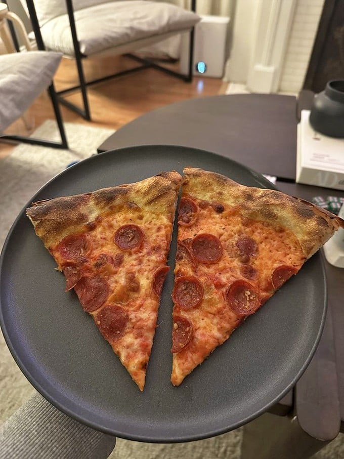 Two slices of pepperoni perfection on a plate. Those crispy-edged cups holding spicy oil are what pizza dreams are made of.