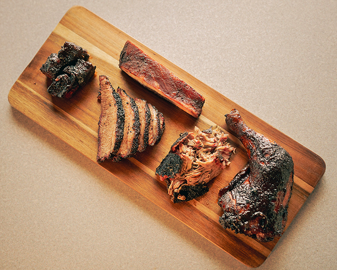 A wooden board showcasing barbecue's greatest hits. This isn't just dinner; it's a flavor concert with multiple encores and standing ovations.