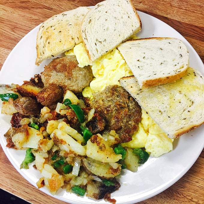 When breakfast means business: eggs, sausage, and home fries arranged like edible artwork on a canvas of simple white diner china.