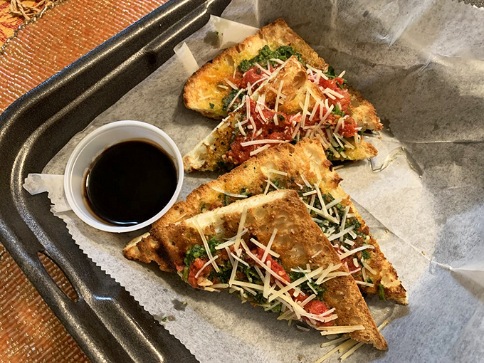 Bruschetta triangles that crunch like autumn leaves, topped with a confetti of fresh ingredients and a shower of cheese&mdash;simple perfection on parchment.
