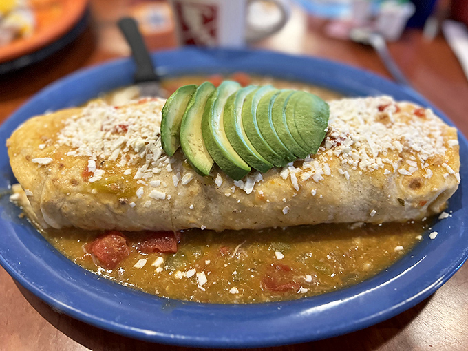 This isn't just a burrito—it's architectural genius wrapped in a tortilla, crowned with avocado and swimming in green chili worthy of its own Colorado zip code.