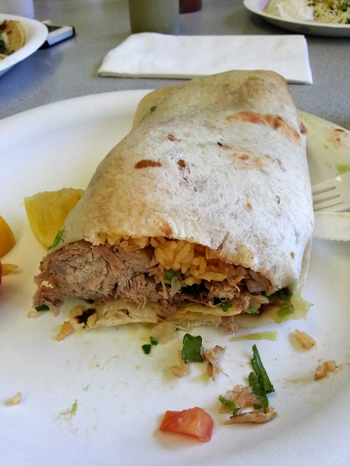 The carnitas burrito, opened slightly to reveal its treasures, sits on its silver throne of foil like Mexican royalty waiting to be crowned with your salsa of choice.