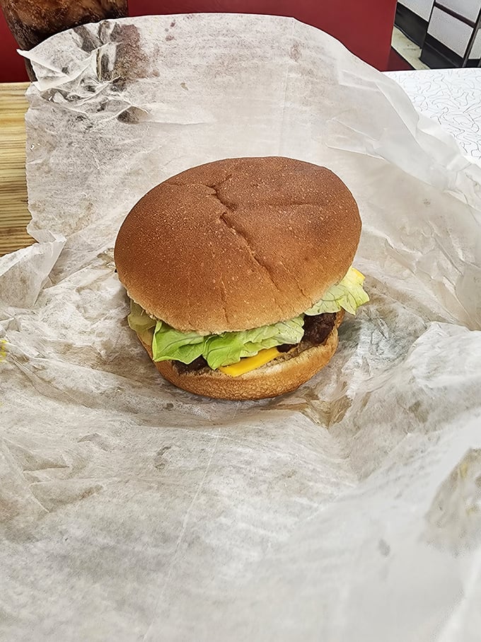 No towering food stack requiring jaw dislocation here&mdash;just an honest hamburger with fresh lettuce on a perfectly toasted bun, wrapped in wax paper nostalgia.