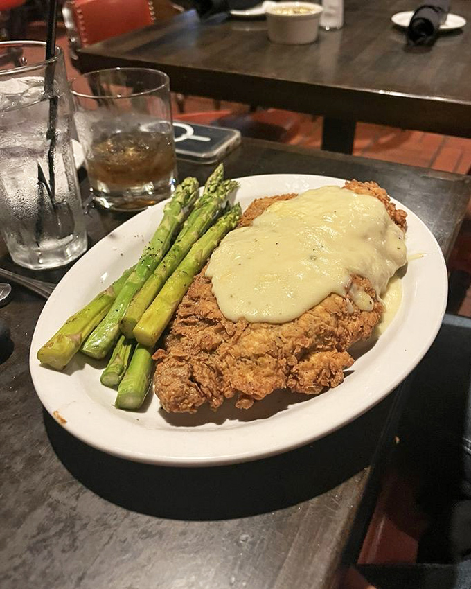 Chicken fried steak wearing its cream gravy like a royal robe, with asparagus standing at attention alongside&mdash;comfort food elevated to art form.