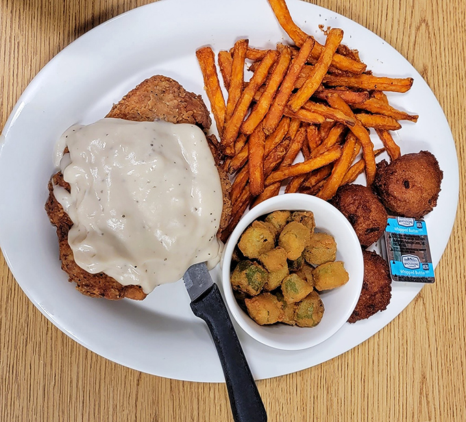 Country-fried steak wearing its gravy like a designer suit, with sweet potato fries that would make a vegetable skeptic reconsider.