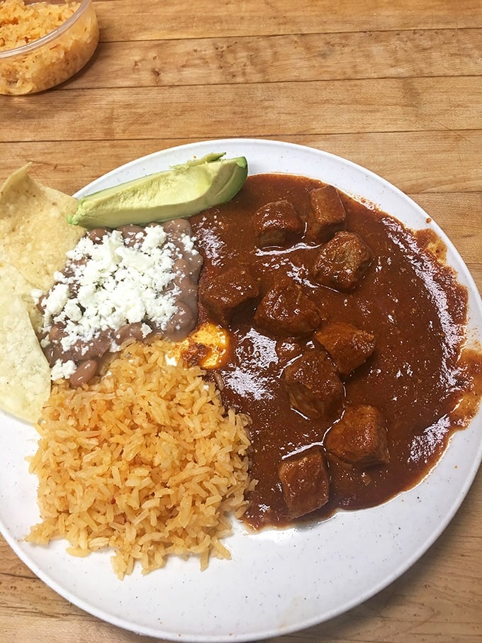 A plate that proves heaven exists on earth. Rice, beans, and chile colorado&mdash;the holy trinity of comfort that makes you want to hug the chef.