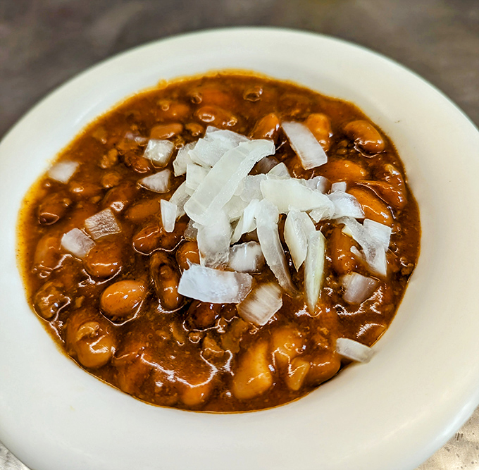 A bowl of their famous chile with beans, topped with diced onions&mdash;proof that sometimes the most unassuming dishes carry the most profound flavors.
