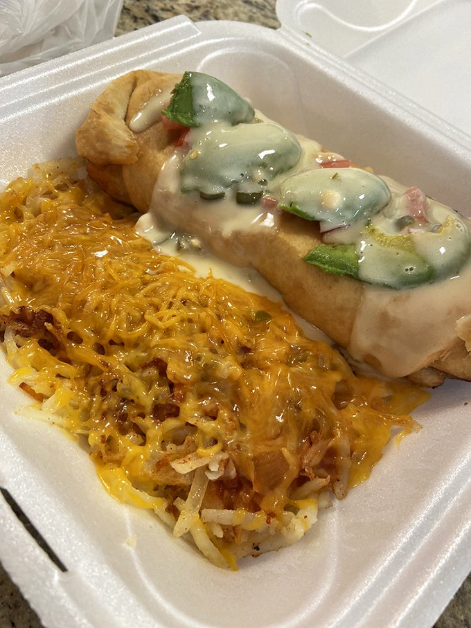 When breakfast and lunch can't decide who's in charge, you get this glorious chimichanga smothered in cheese alongside hash browns that deserve their own fan club.