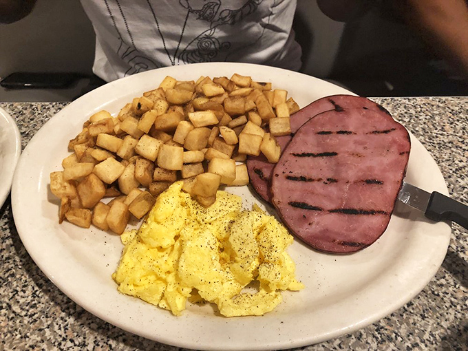 The country breakfast plate featuring ham, eggs, and golden hash browns - morning comfort food at its finest.