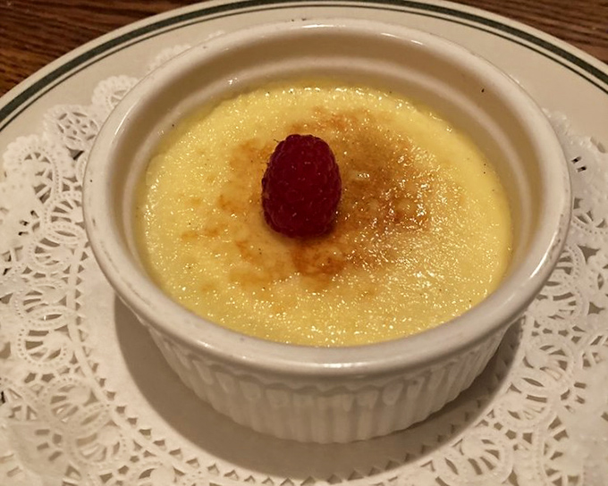 Cr&egrave;me br&ucirc;l&eacute;e with a crust that cracks like thin ice on a perfect winter morning. That lone raspberry is the cherry on top&mdash;except it's a raspberry.