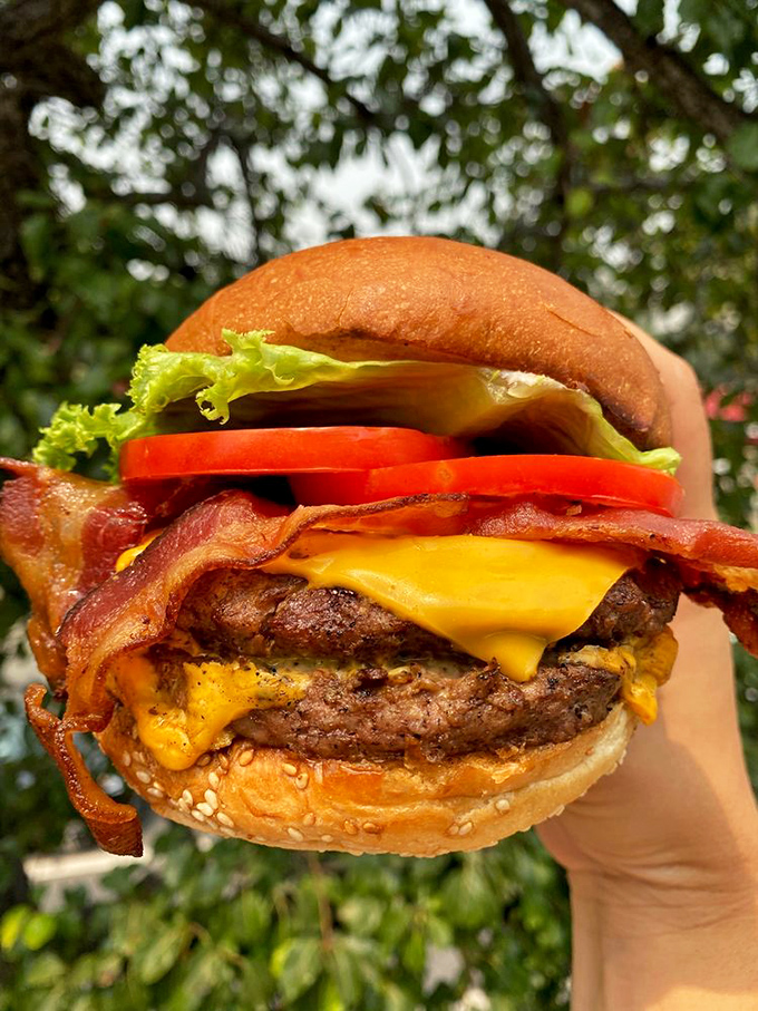 A burger that requires both hands and a strategy—melted cheese cascading down like a yellow waterfall of joy.
