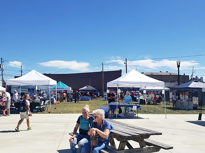 Nothing says "authentic community" like seniors chatting on a bench while farmers market tents billow in the background&mdash;small-town America's version of social networking.