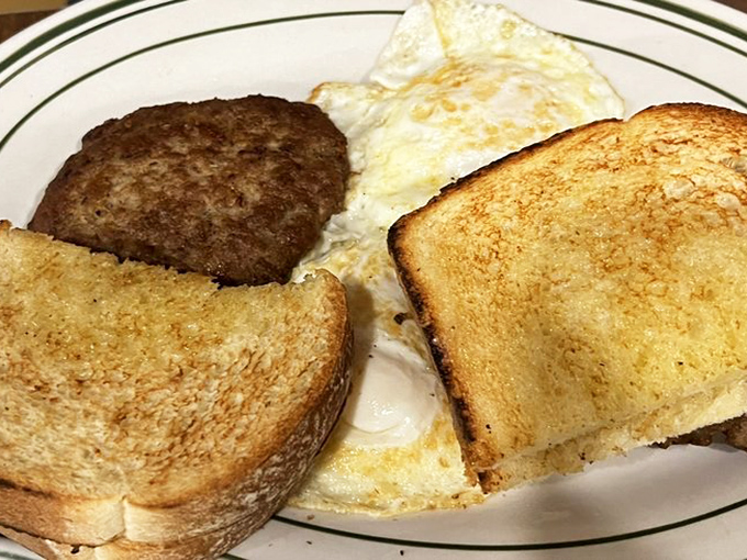 The breakfast trinity: perfectly cooked eggs, golden toast, and a sausage patty that means serious business.