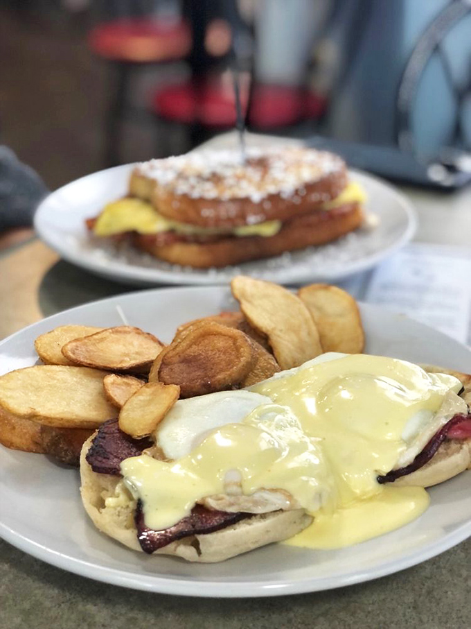 Eggs Benedict reimagined with a thick slice of ham and creamy hollandaise cascading down like a yellow waterfall of happiness.