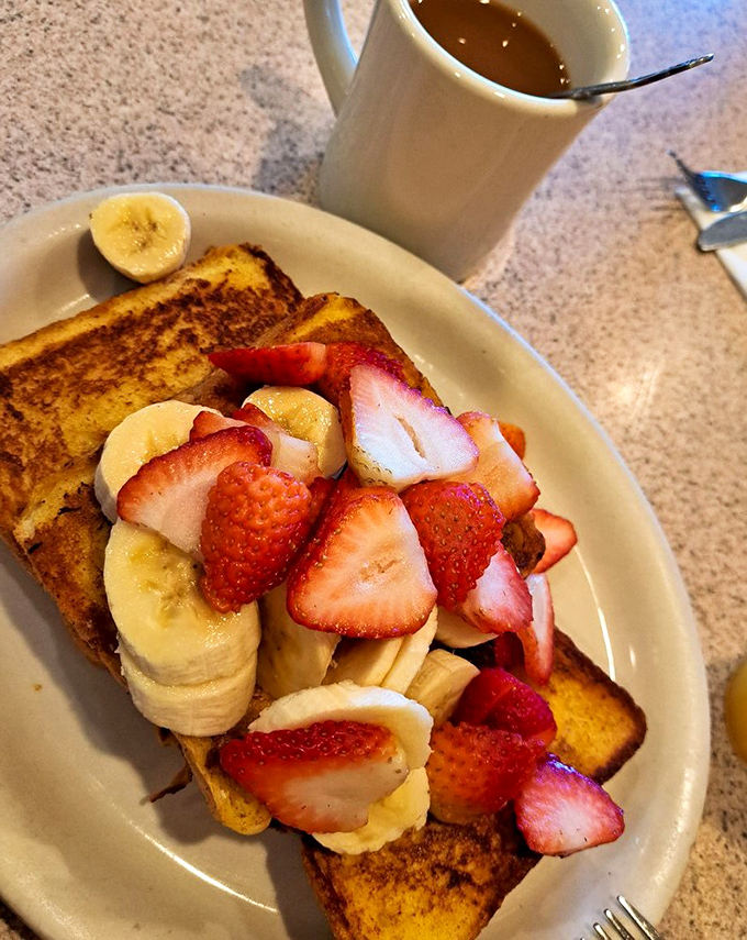 French toast transformed into a fruit-laden island of breakfast bliss. Those strawberries and bananas aren't just toppings&mdash;they're making a statement about starting your day right.