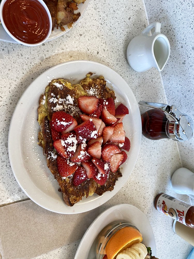 The famous French toast in its natural habitat, crowned with fresh strawberries. This isn't breakfast&mdash;it's edible therapy that makes everything right with the world.