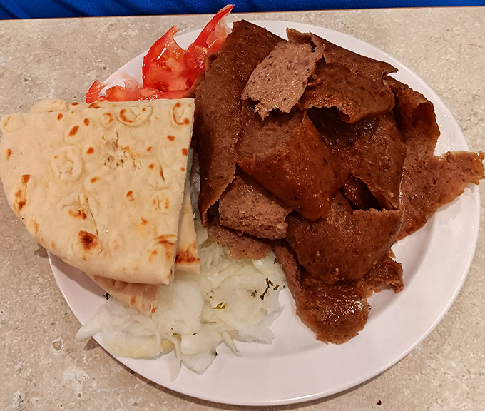 Building the perfect bite: pita, gyro meat, tomato, and a touch of tzatziki. Architecture has never been so delicious.