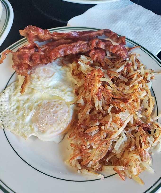 The breakfast trifecta: crispy bacon, perfectly fried eggs, and those hash browns that somehow manage to be both crispy and tender.