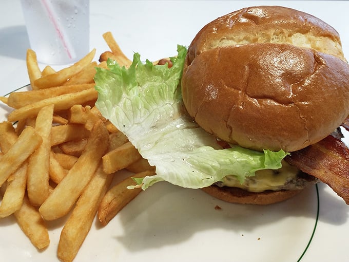 A burger that requires both hands and several napkins, paired with fries that could make a French chef nod in approval. This is lunch done right.