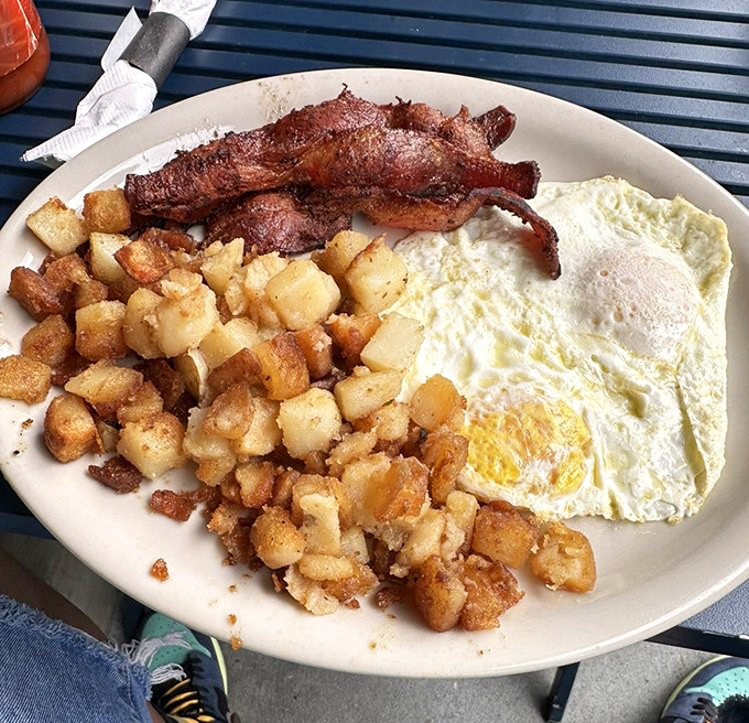 The holy trinity of breakfast: crispy bacon, eggs cooked just right, and home fries with that perfect crust. Morning salvation!