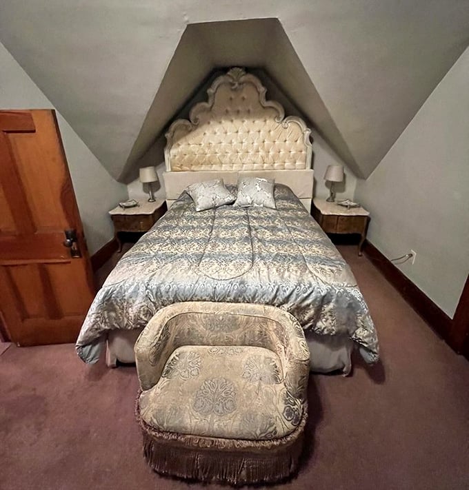 Tucked beneath the eaves, this regal bedroom with its tufted headboard and matching footstool offers dreams of courtly romance.