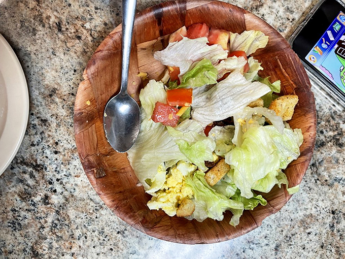Even the house salad gets respect here – fresh greens, tomatoes, and croutons served in a wooden bowl that somehow makes everything taste better.