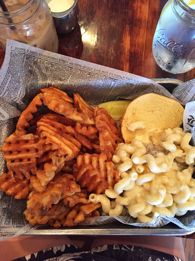 Waffle fries, mac and cheese, and a pickle—the holy trinity of comfort food, presented on newspaper like the headline-worthy meal it is.