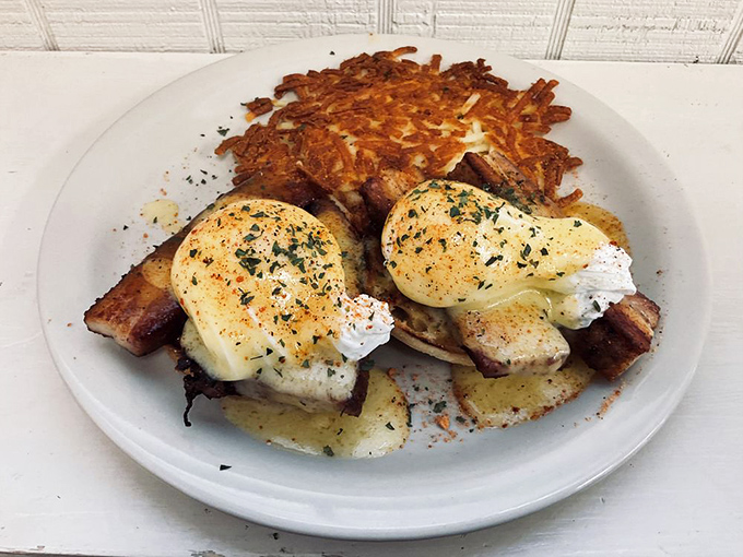 Eggs Benedict reimagined with perfectly poached eggs atop crispy hash browns. The hollandaise sauce glistens like Florida morning sunshine after a brief summer shower. 