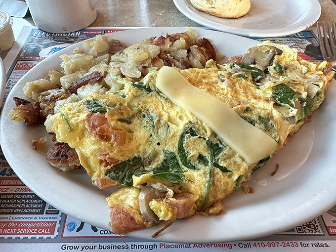 An omelet that doesn't just include vegetables but celebrates them, paired with home fries that achieve the perfect crisp-to-tender ratio.