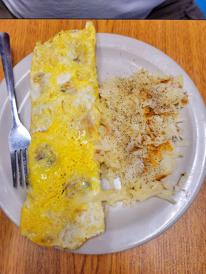 This omelet has achieved that perfect balance between fluffy and substantial. The hash browns beside it look like they've been kissed by the breakfast gods.