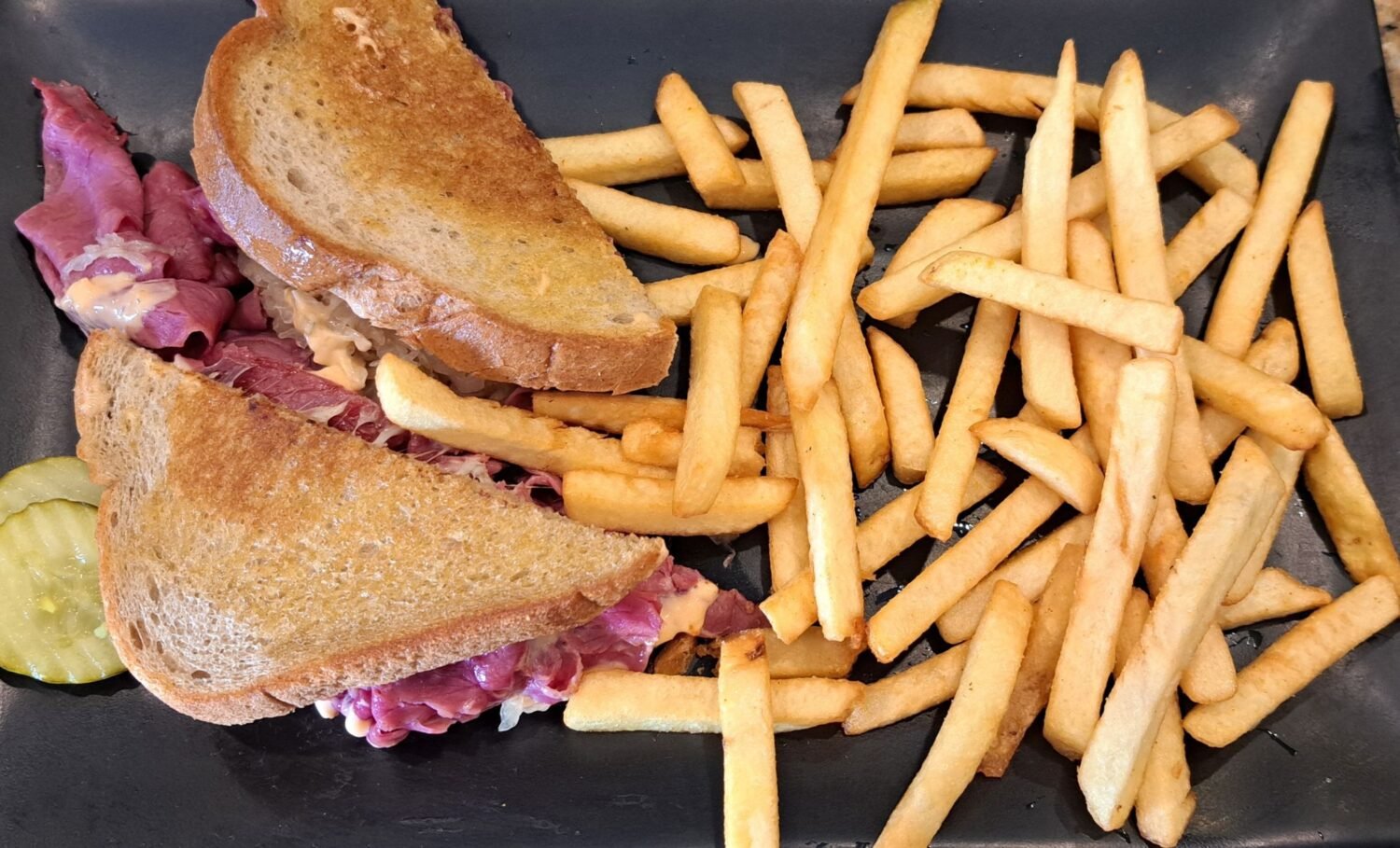 A sandwich that requires both hands and zero shame. Piled high with roast beef and paired with fries that look like they've been double-dipped in deliciousness.