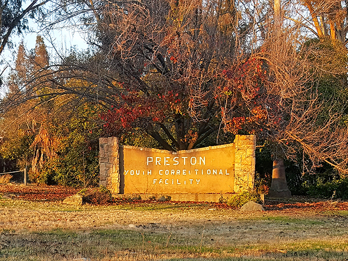 The sun casts a golden glow on this entrance sign, a bureaucratic label that hardly captures the architectural wonder and complex history waiting beyond.