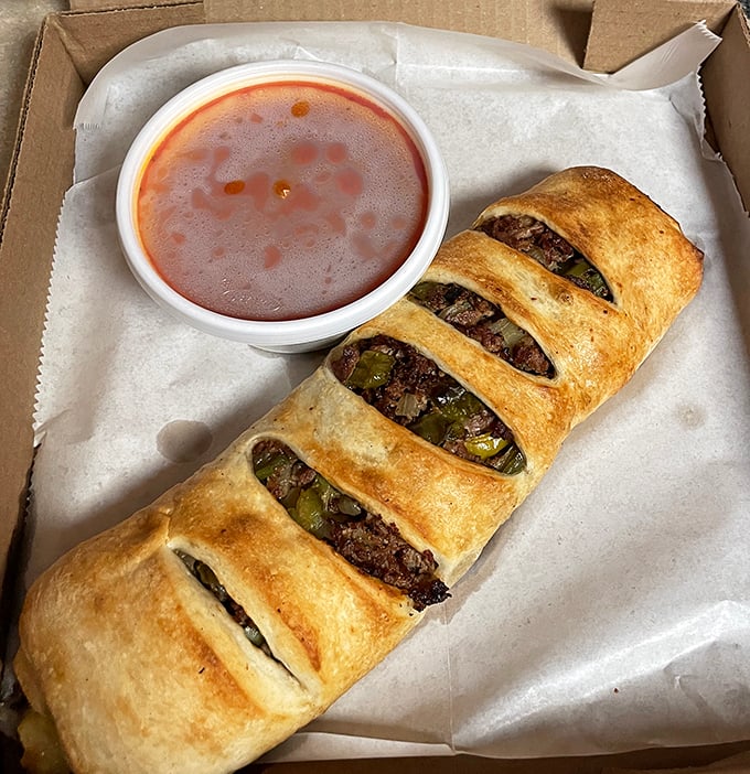 The stromboli&mdash;essentially a pizza that decided to roll itself up for your portable eating pleasure. Meat and peppers peek through those perfect slashes.