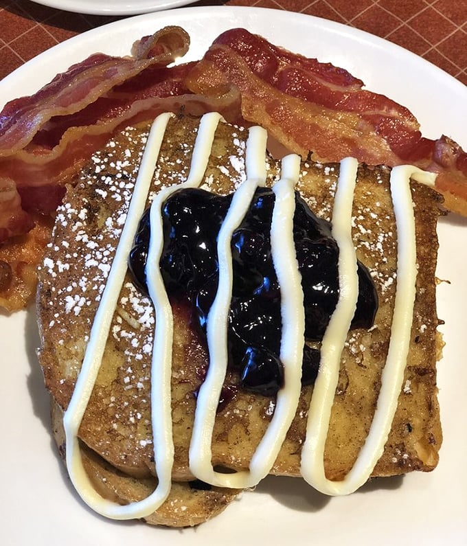 French toast living its best life—powdered sugar, blueberry compote, cream drizzle, and bacon. Breakfast dreams do come true in Ohio.