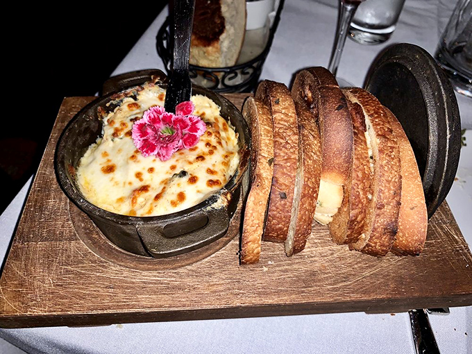 This seafood dip arrives like a warm embrace in a cast iron skillet, with toasted bread slices standing ready for their delicious duty.