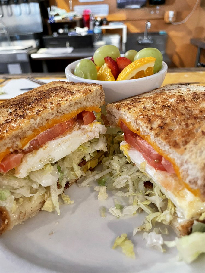 This breakfast sandwich isn't just stacked&mdash;it's architecturally sound. Fresh veggies, melted cheese, and eggs between perfectly toasted bread with fruit playing supporting roles.