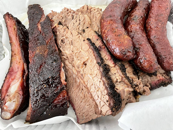 The holy trinity of Texas BBQ: brisket with that glistening bark, pork ribs with the perfect pull, and sausage with that satisfying snap.