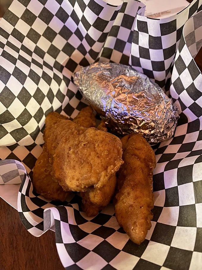 Golden-fried chicken tenders nestled beside a foil-wrapped baked potato &ndash; comfort food that speaks the universal language of "everything's gonna be alright."